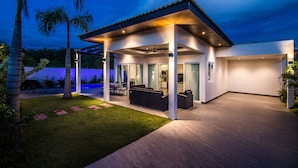 Uma casa moderna com varanda coberta, piscina e gramado bem cuidado.