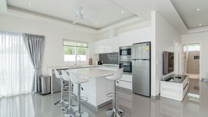 Uma cozinha moderna com armários brancos, eletrodomésticos de aço inoxidável e uma ilha central com banquetas.