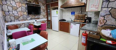 Restaurante com paredes de pedra, televisão, área de cozinha e extintor de incêndio.