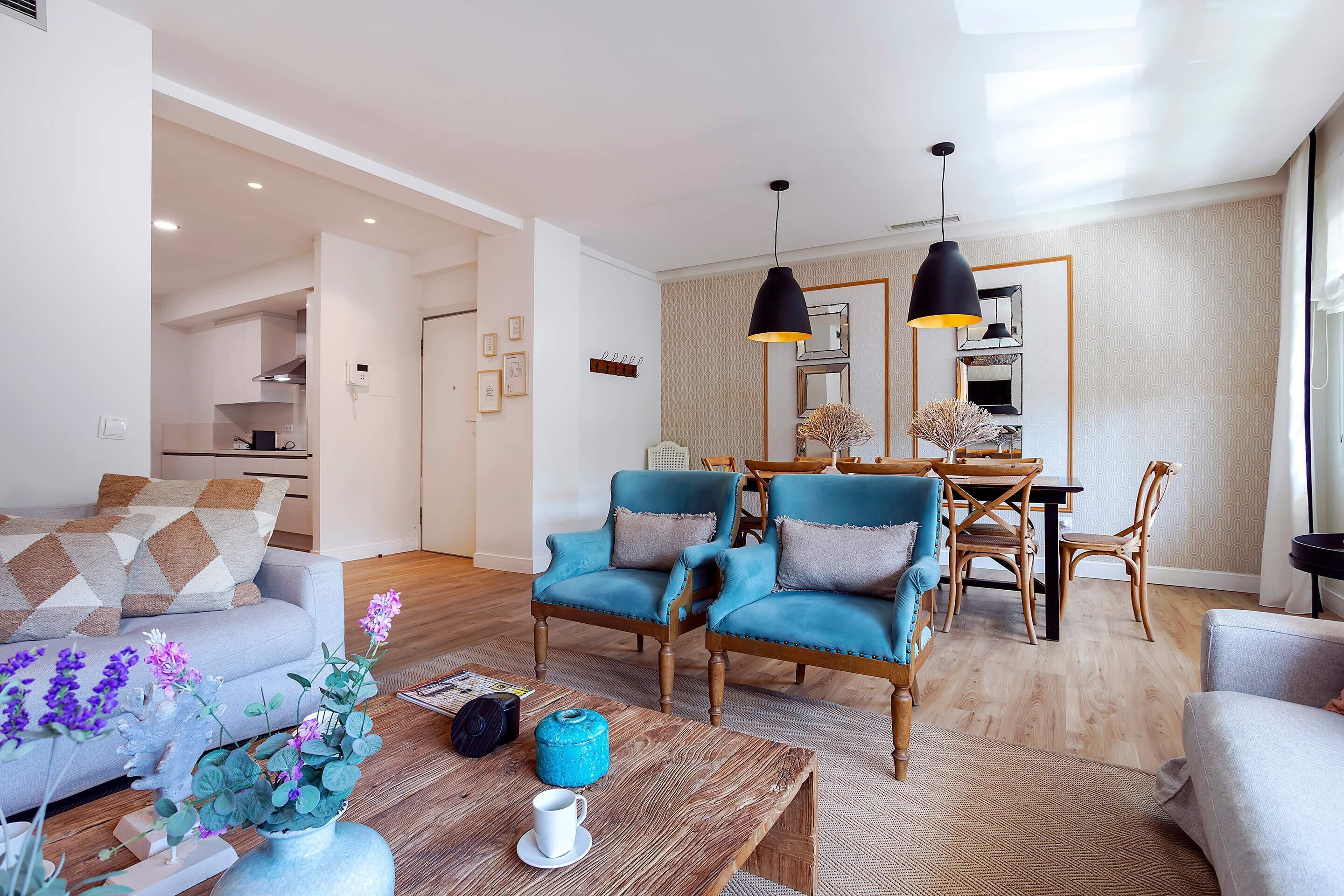 Uma sala de estar moderna com um sofá, duas poltronas, uma mesa de centro e um espaço de jantar com mesa e cadeiras.