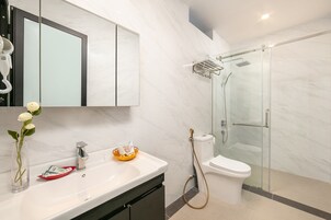 Uma casa de banho moderna com lavatório branco, cabine de duche em vidro e sanita.