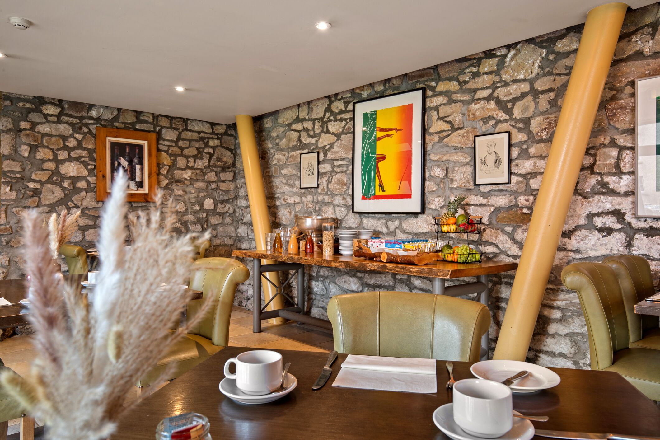 Uma sala de jantar com parede de pedra, mesa de madeira e cadeiras de couro.