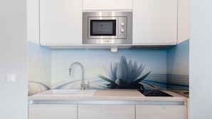 Uma cozinha moderna com micro-ondas embutido, pia e painel decorativo.