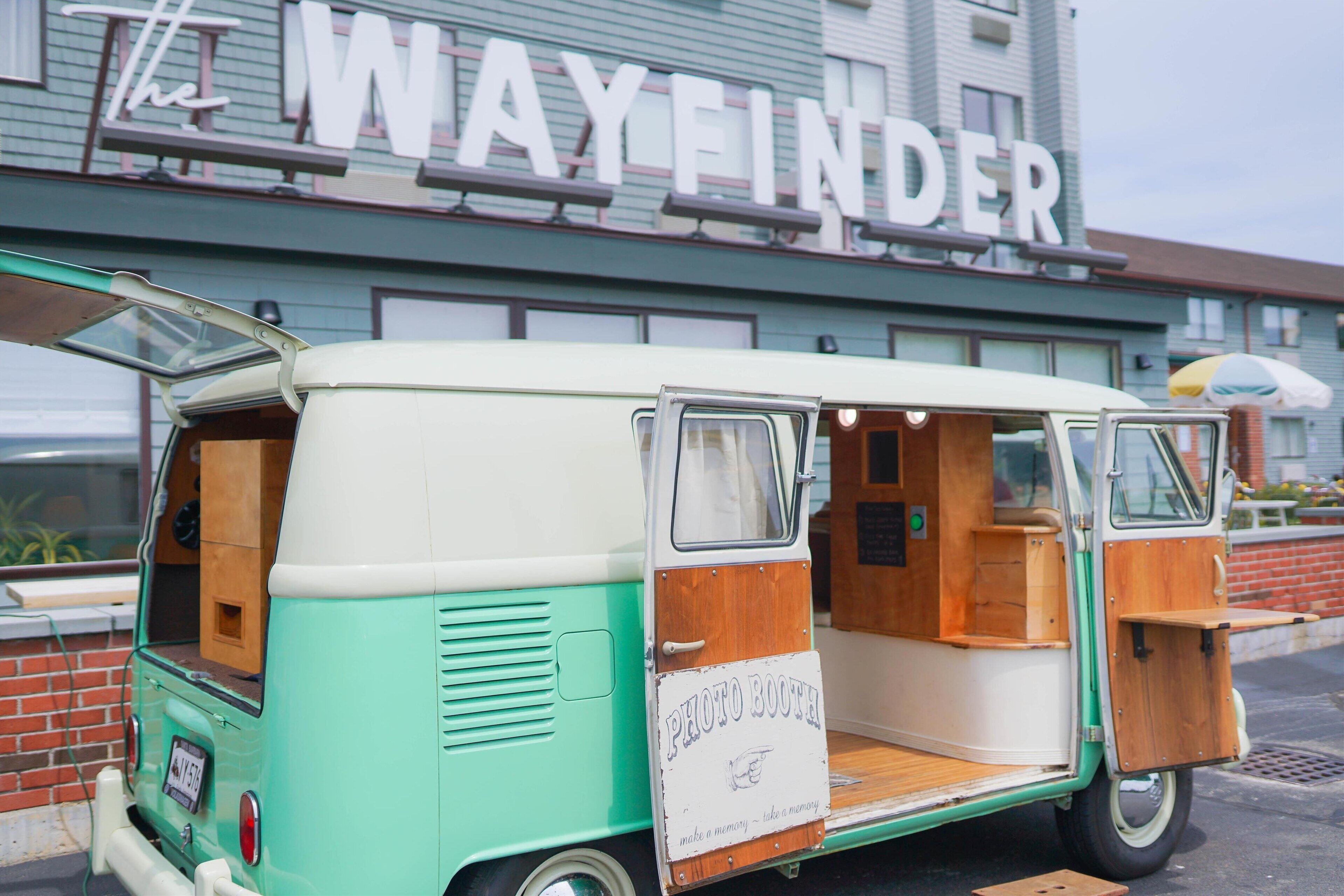 Uma van antiga com um letreiro que diz 'PHOTO BOOTH' e um letreiro acima que diz 'WAYFINDER'.