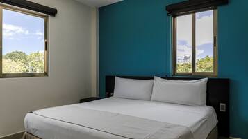 Quarto com cama, duas janelas e parede azul-turquesa.