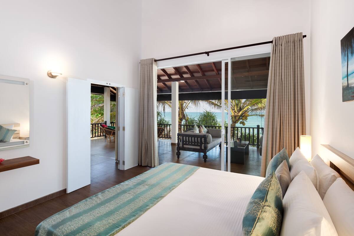 Quarto com cama grande, vista para a varanda e porta para área externa.