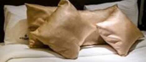 Uma cama com cabeceira escura e várias almofadas.