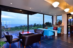 Interior moderno com uma grande janela com vista para uma paisagem deslumbrante, área de estar com sofá azul e um armário de madeira.