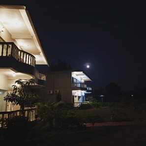 Um edifício com várias andares, varandas, uma escadaria e uma lua crescente no céu.