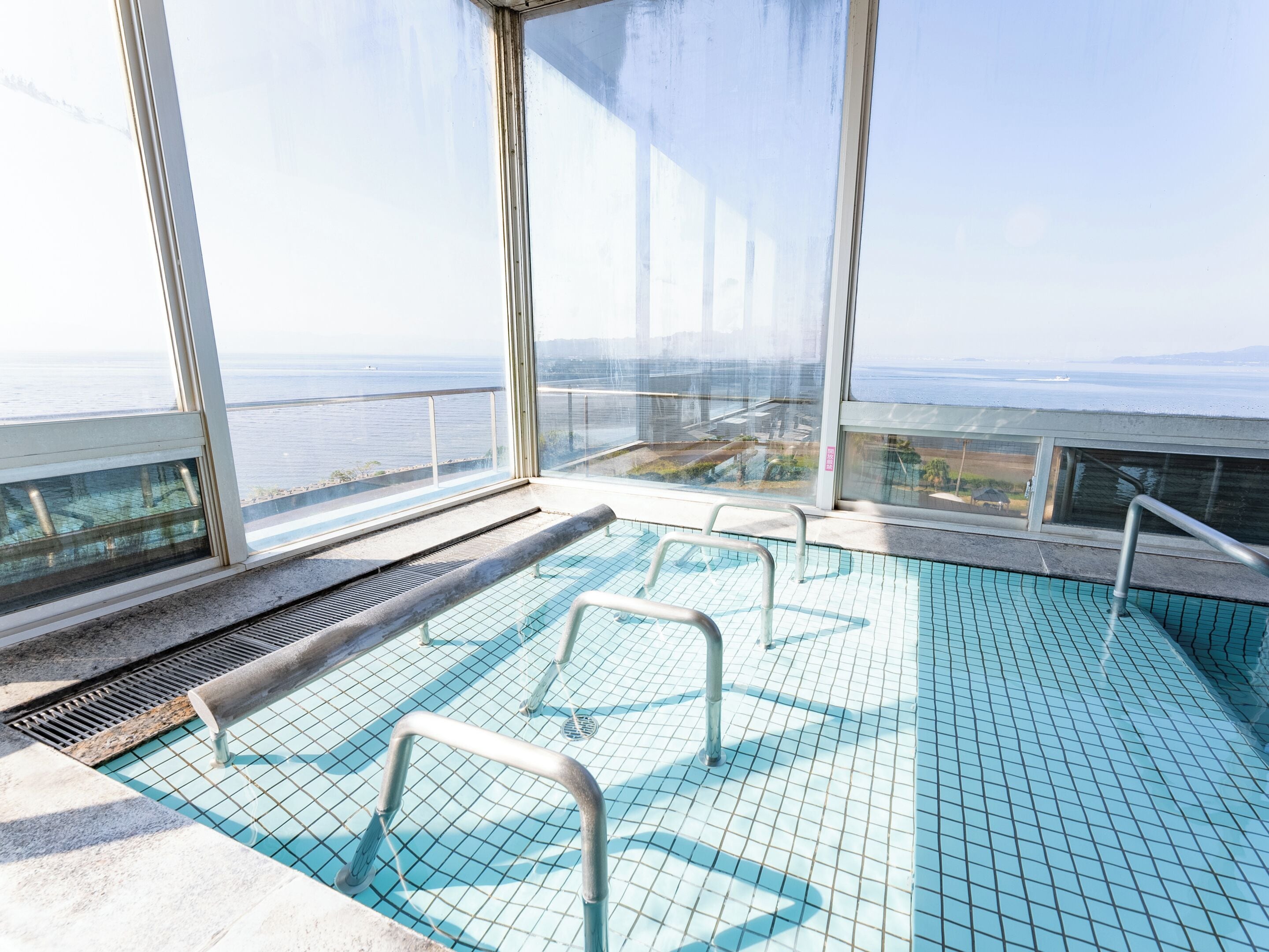 Piscina interior com vista clara para o oceano e uma ponte ao longe.