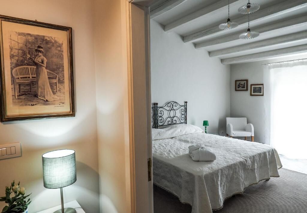 Quarto com cama, uma cadeira, um abajur e um quadro pendurado na parede.