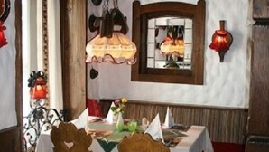 Uma área de refeições com mesa e cadeiras de madeira, luminária pendente e janela com vista.