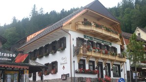 Um edifício europeu tradicional com um letreiro de restaurante, varandas de madeira e caixas com flores.