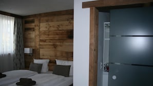 Quarto de hotel com painéis de madeira, cama com roupa de cama branca e porta moderna.