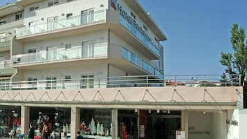 Um hotel com vários andares, varandas e uma loja no térreo exibindo diversos itens.