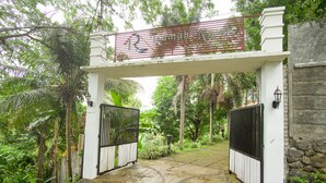 Uma entrada fechada com portão de metal e arco branco.