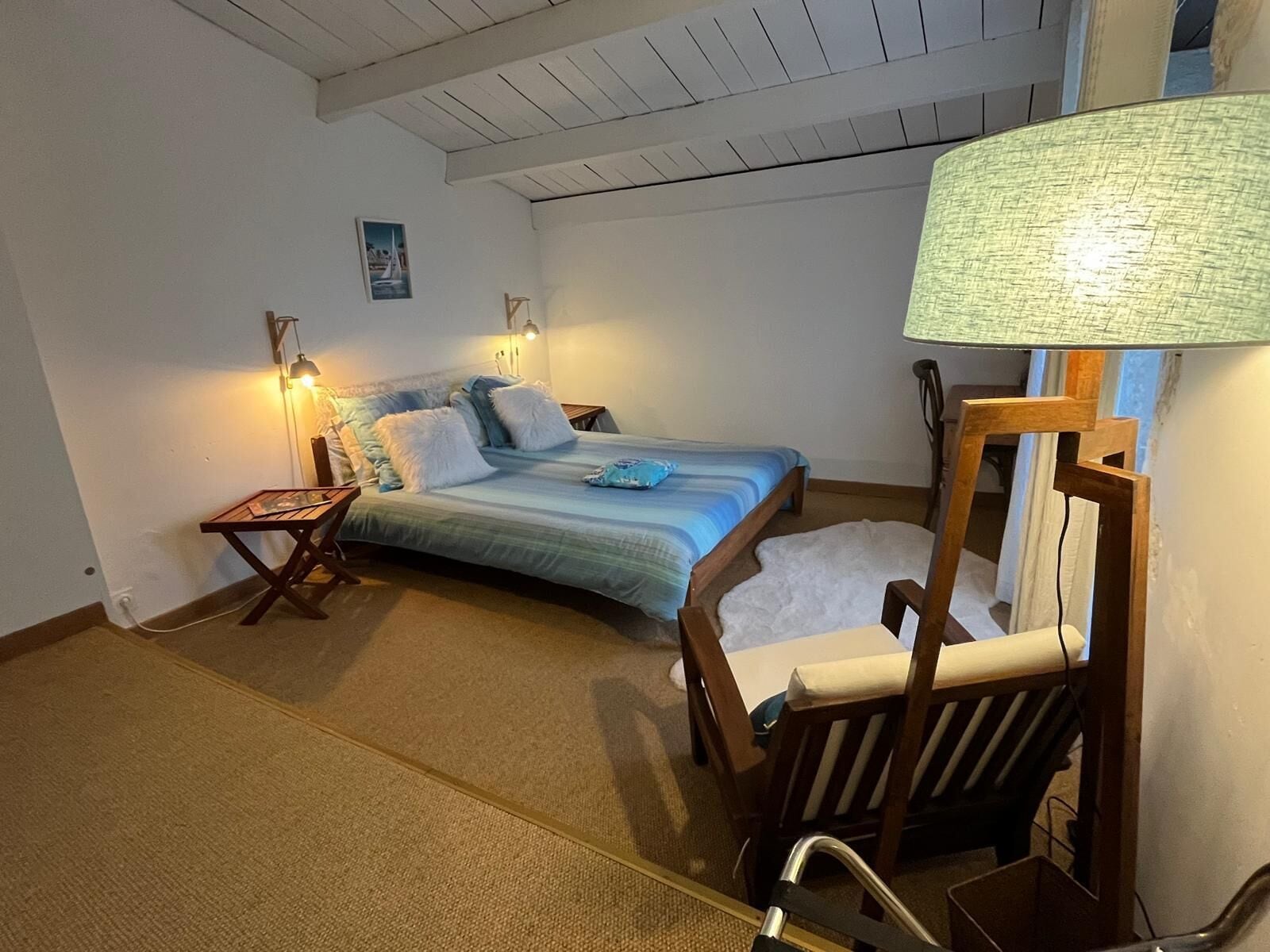 Quarto com cama, mesas de cabeceira, uma cadeira e um abajur.