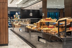Um interior moderno com um balcão extenso exibindo uma variedade de produtos de panificação e doces.