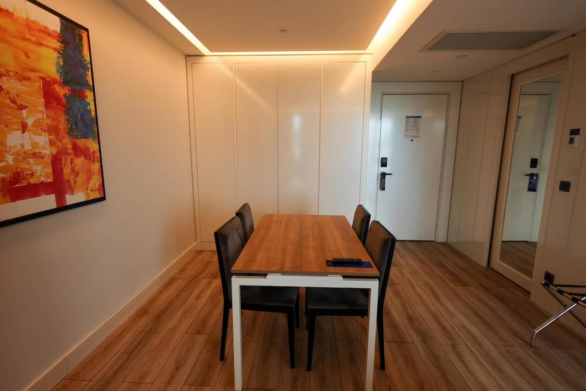 Uma sala de conferências com uma mesa de madeira e cadeiras pretas, um quadro na parede e uma porta ao fundo.