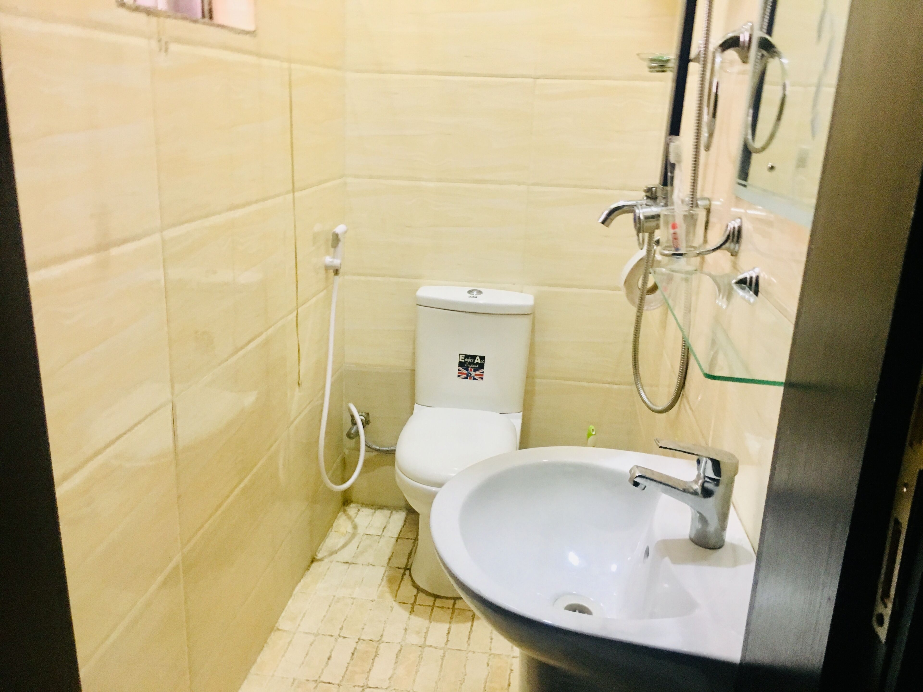 Uma casa de banho pequena com lavatório branco, sanita e chuveiro.