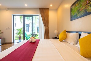 Quarto de hotel com cama, um tapete vermelho, vista para o exterior e um quadro na parede.