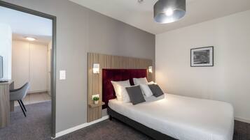 Quarto de hotel moderno com uma cama grande, uma escrivaninha e uma cadeira.