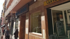 Um hotel com uma placa indicando "HOTEL MAYNA" e um bar chamado "CERVECERÍA", com um quadro de menu visível.