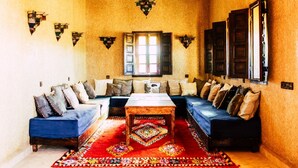 Uma sala de estar acolhedora com um sofá azul, uma mesa de centro de madeira e um tapete colorido.