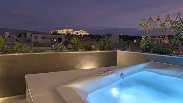 Uma banheira de hidromassagem no terraço com vista para o horizonte urbano ao entardecer.
