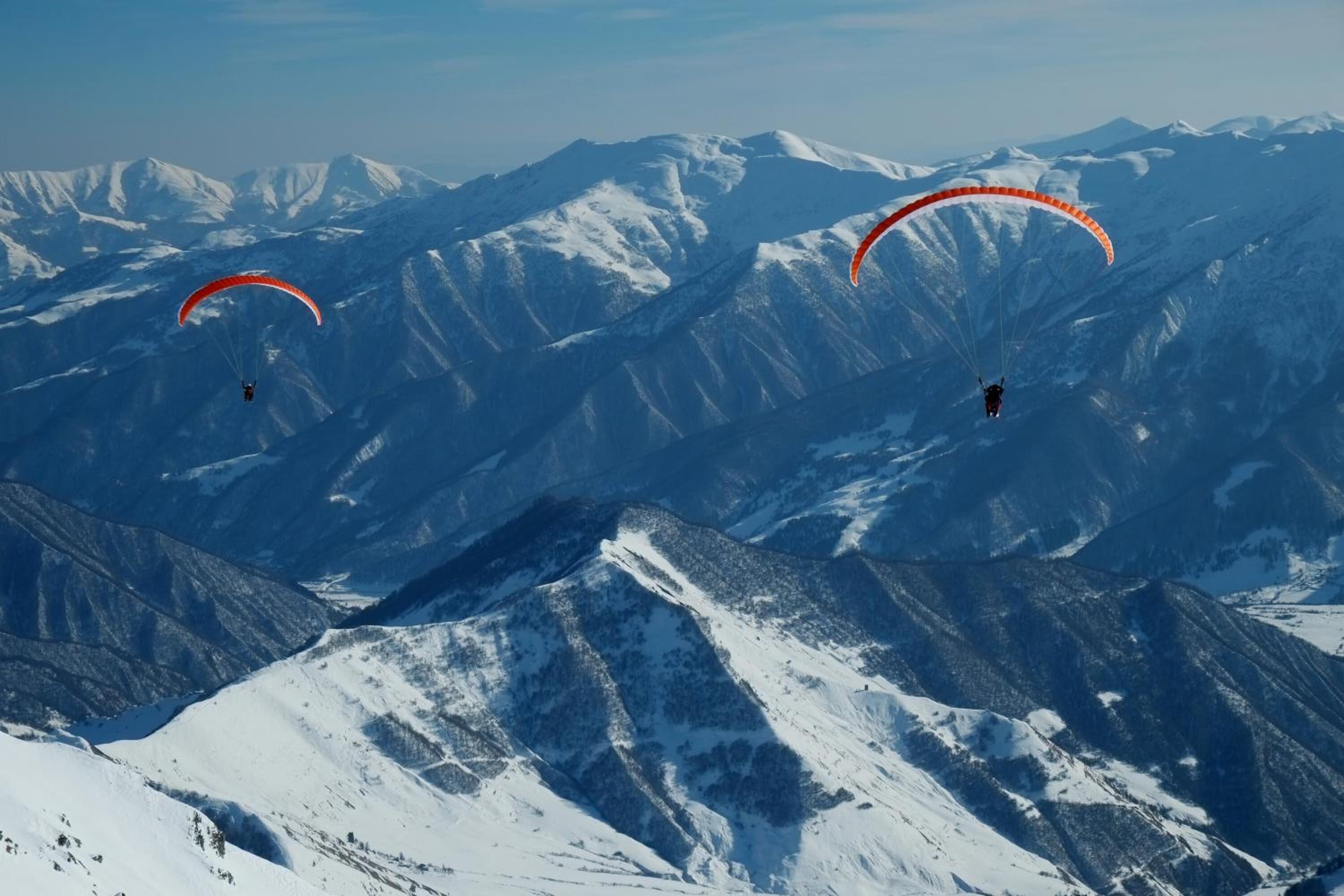 Paisagem montanhosa com dois parapentes.