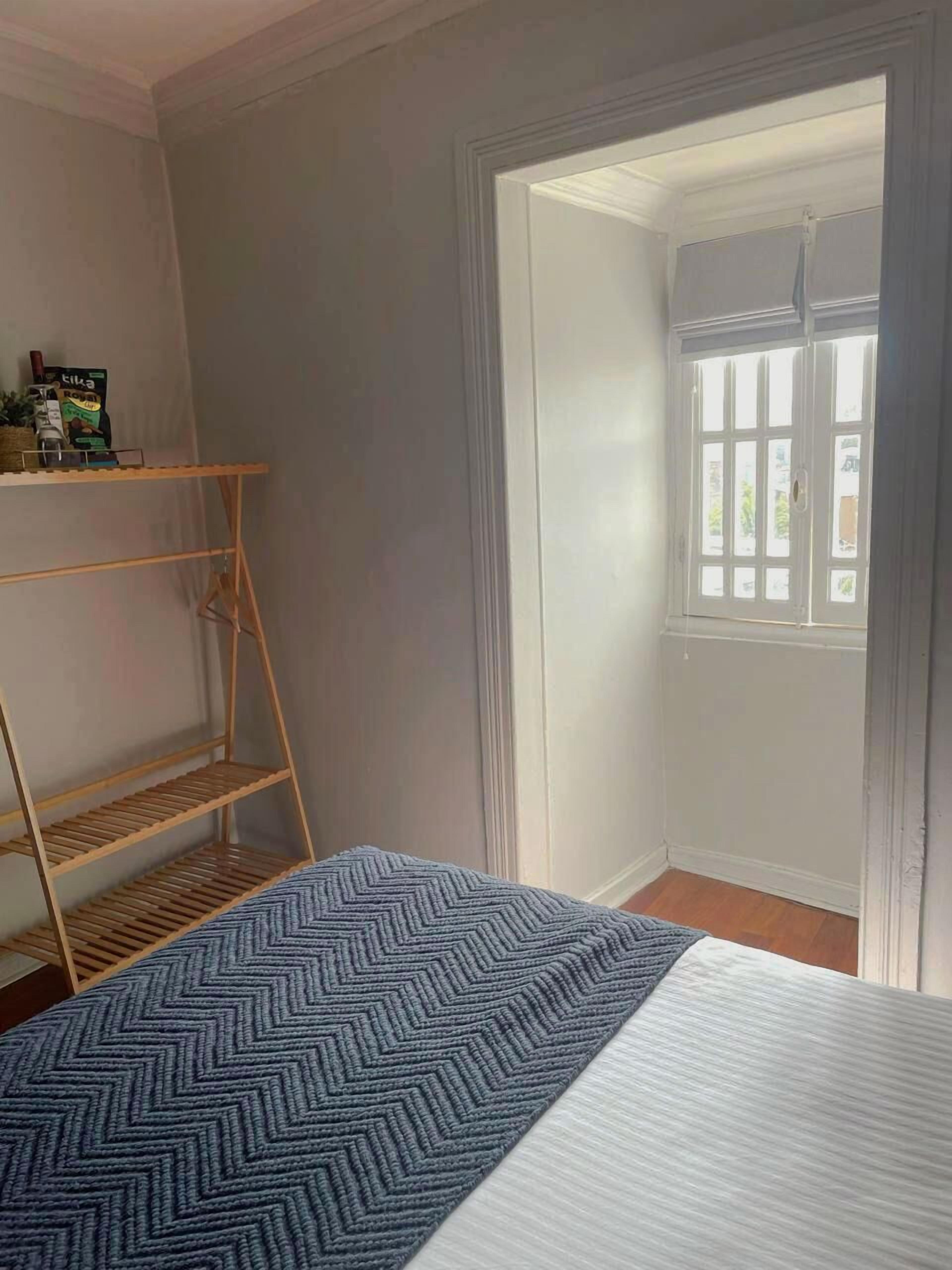 Um quarto com uma cama, uma prateleira de madeira e uma janela.