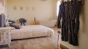 Quarto com cama, poltrona, banheira e porta-roupas.