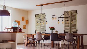 Uma sala de jantar com mesa de madeira, cadeiras e luminária pendente.
