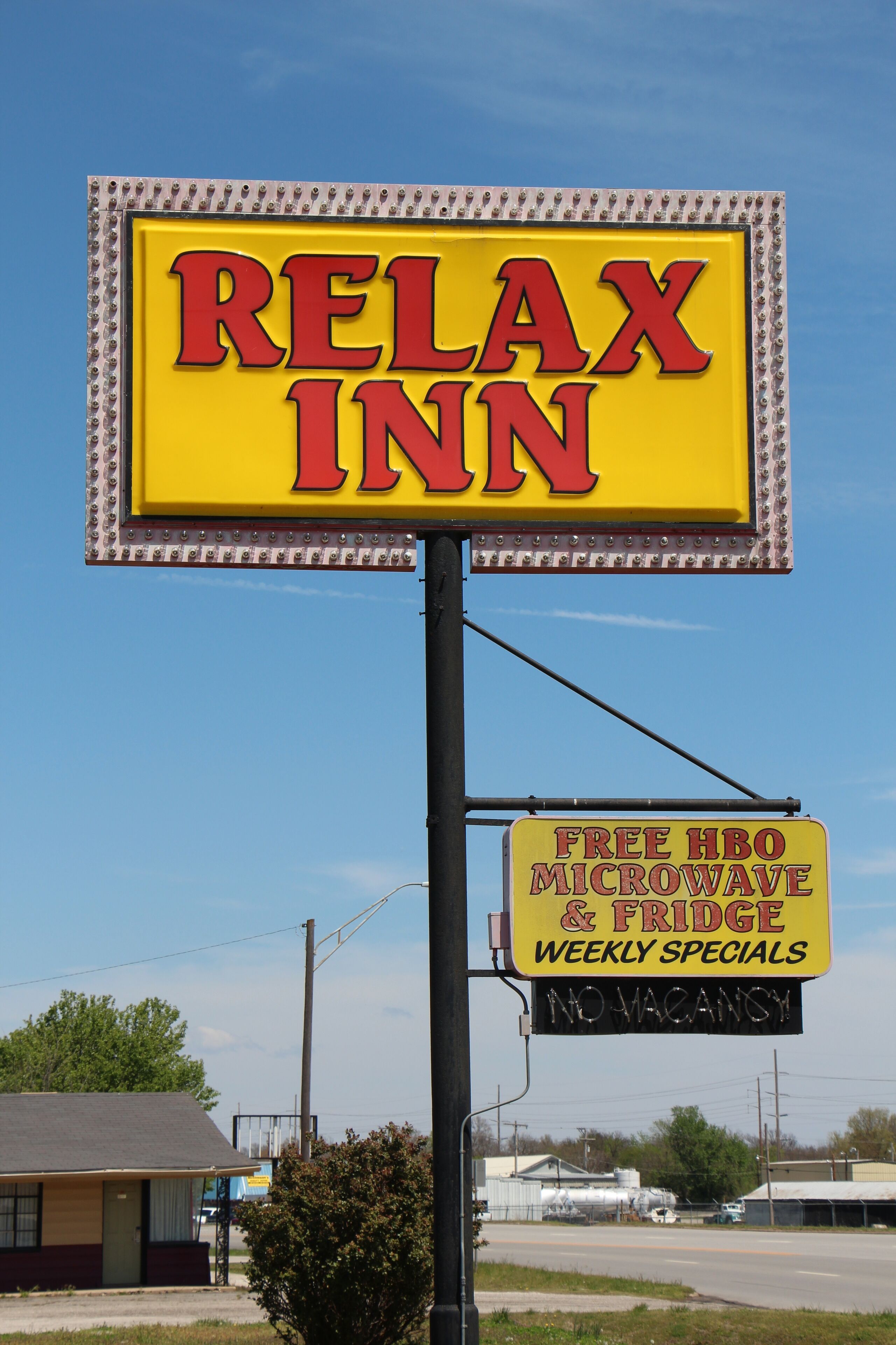 Placa para o 'Relax Inn', com comodidades como HBO gratuito, micro-ondas e geladeira, além de ofertas semanais.