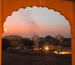 Acampamento no deserto com tendas e fogueira.