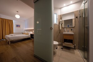 Quarto de hotel moderno com cama, banheiro com chuveiro e vaso sanitário.
