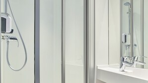 Um banheiro moderno com box de vidro, pia branca e piso revestido de azulejos.
