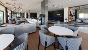 Um hall de hotel moderno com área de estar, balcão de recepção e uma grande janela.