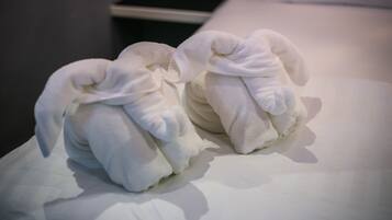 Duas toalhas brancas dobradas sobre uma cama.