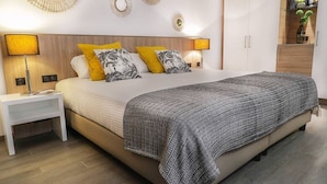 Quarto com cama, luminárias de cabeceira, mesa de cabeceira e guarda-roupa.