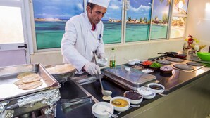 Um chef prepara comida no balcão, com vista para uma praia tropical.
