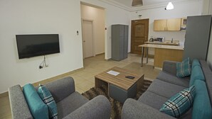 Uma sala de estar moderna com sofás cinzas, uma mesa de centro e uma televisão de tela plana.