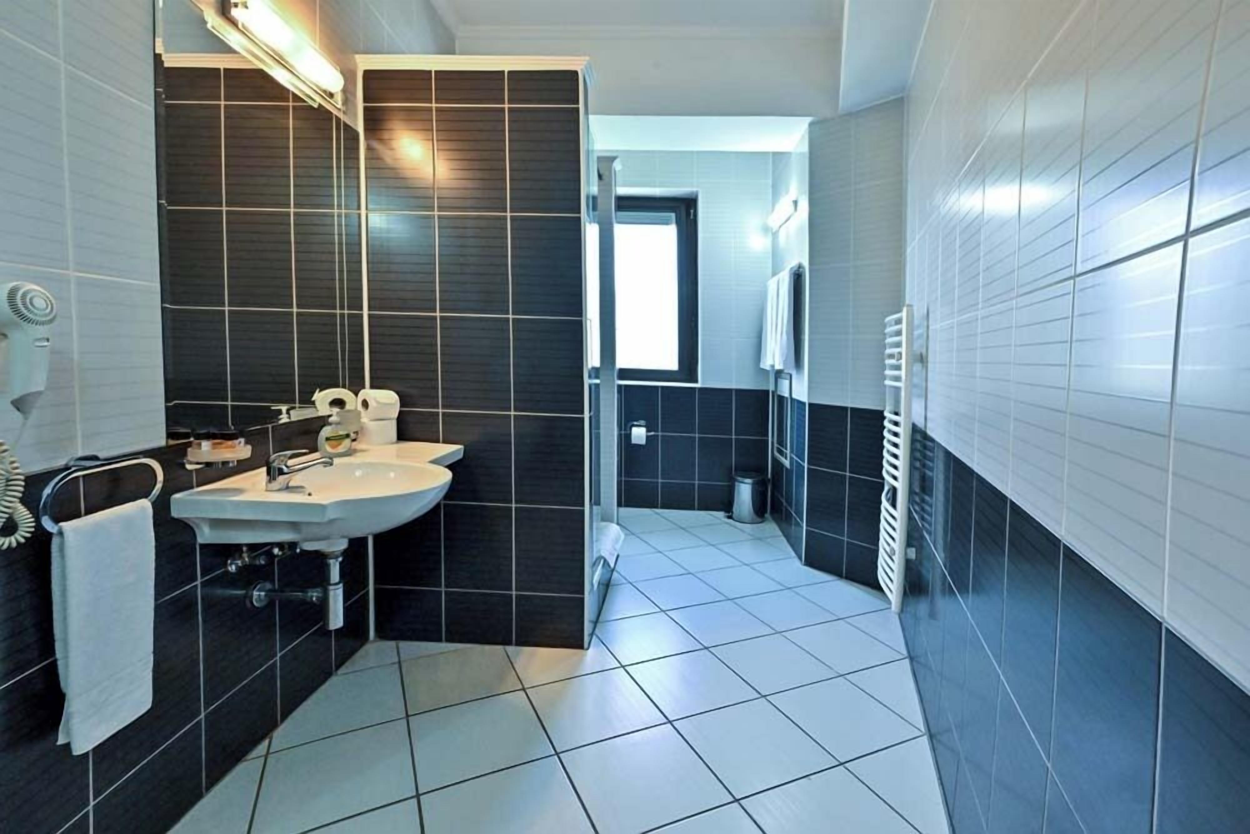 Uma casa de banho moderna com lavatório, espelho e porta-toalhas.