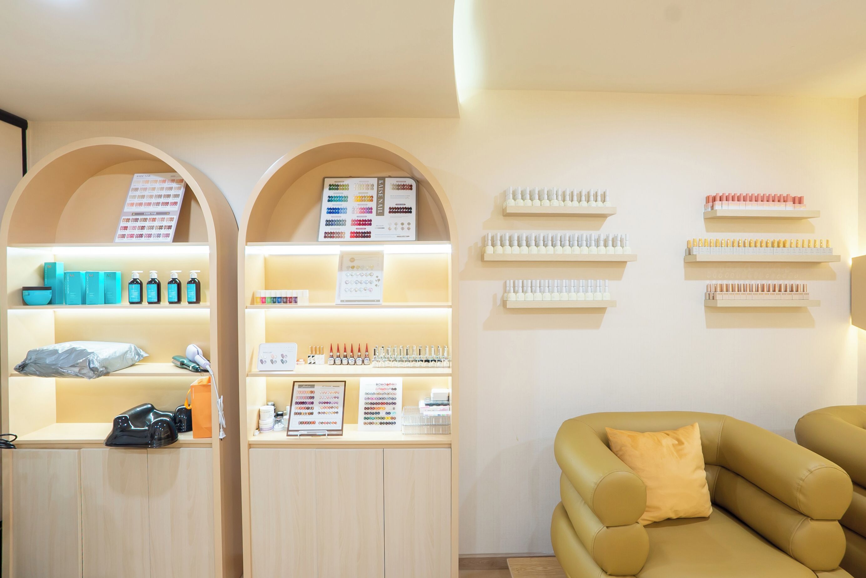 Quarto com sofá bege, um armário de madeira com diversos objetos e prateleiras com produtos.