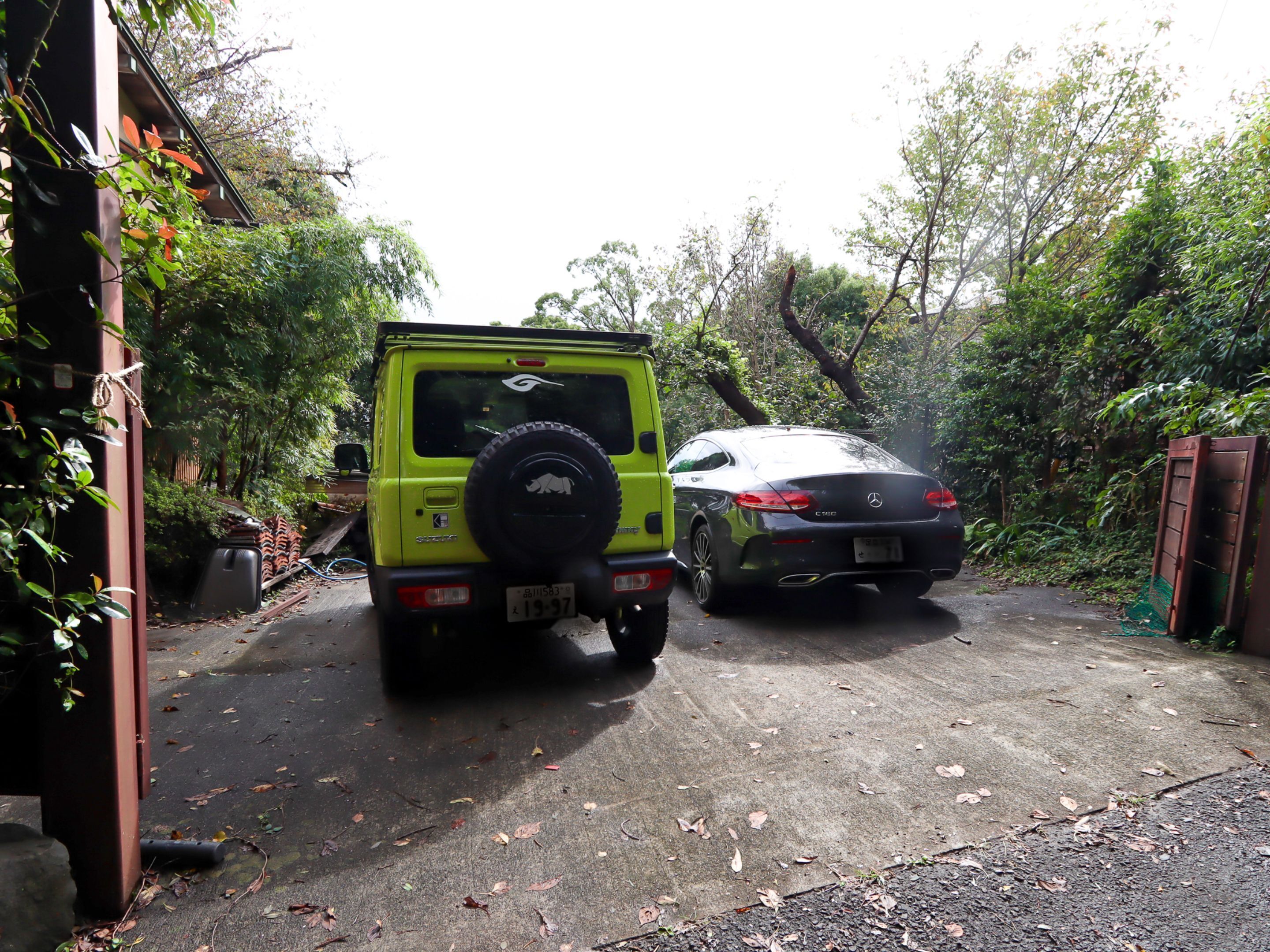 Um veículo estacionado numa entrada de garagem, com uma porta de garagem e uma árvore ao fundo.