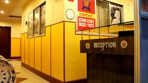 Uma área de recepção com balcão de atendimento identificado com a palavra "RECEPTION" e um aviso com números de contato.