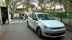 Um carro branco Volkswagen estacionado numa área de estacionamento coberta com chão ladrilhado.