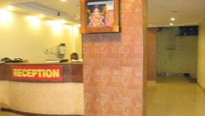 Uma área de recepção com balcão, uma moldura com imagem acima e piso de azulejos.