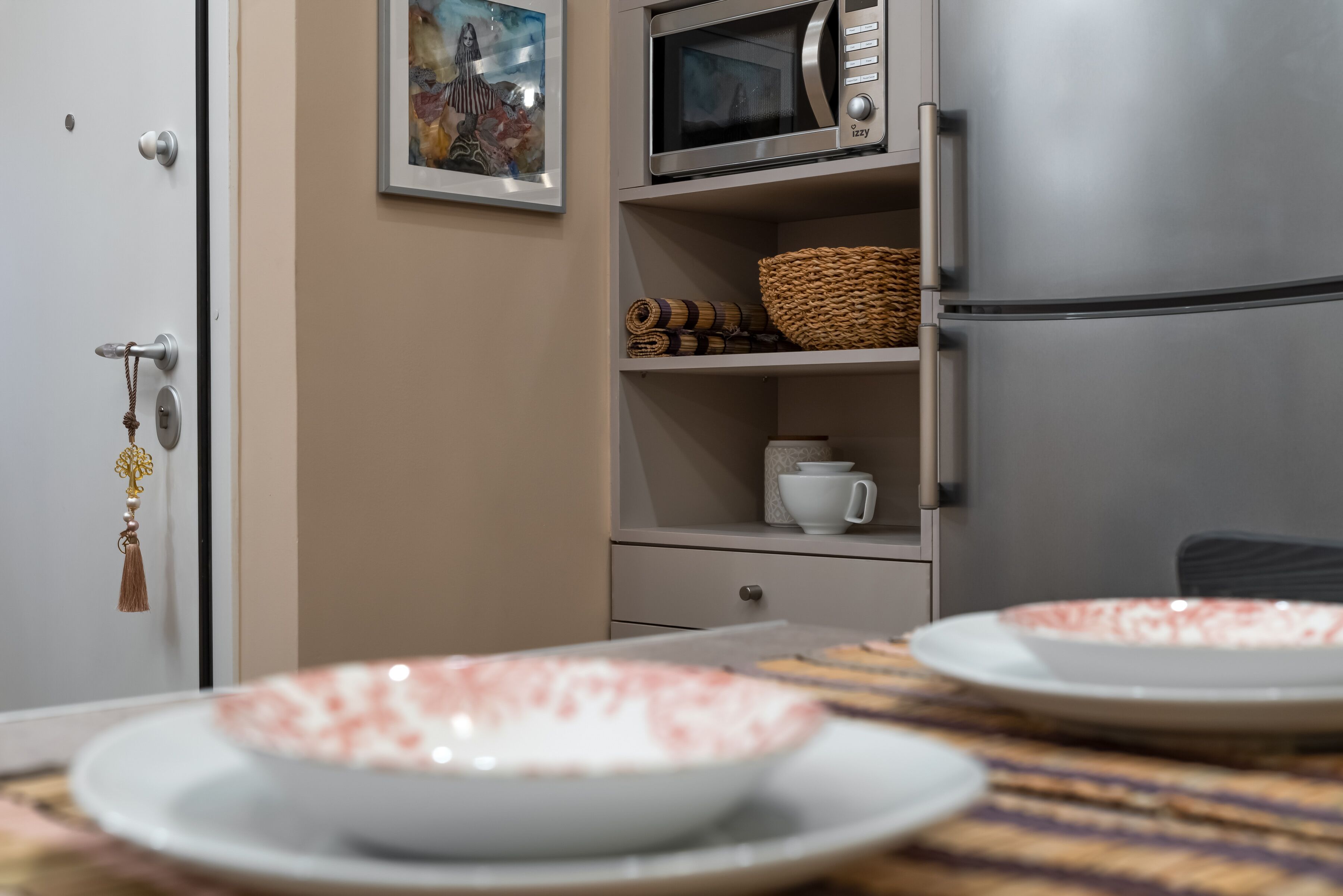 Uma cozinha compacta com micro-ondas, geladeira e prateleiras com utensílios de cozinha.