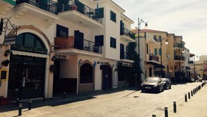 Rua com edifícios com varandas e lojas, incluindo uma placa visível para 'The Secret Garden'.